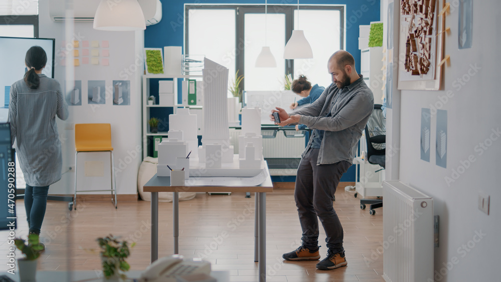 Architect using mobile phone to create blueprints plan with building ...