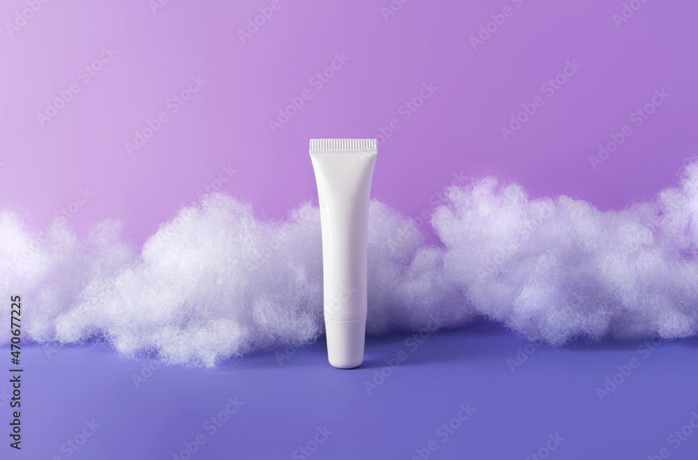Lip balm with fluffy clouds on violet background. Concept care with ...