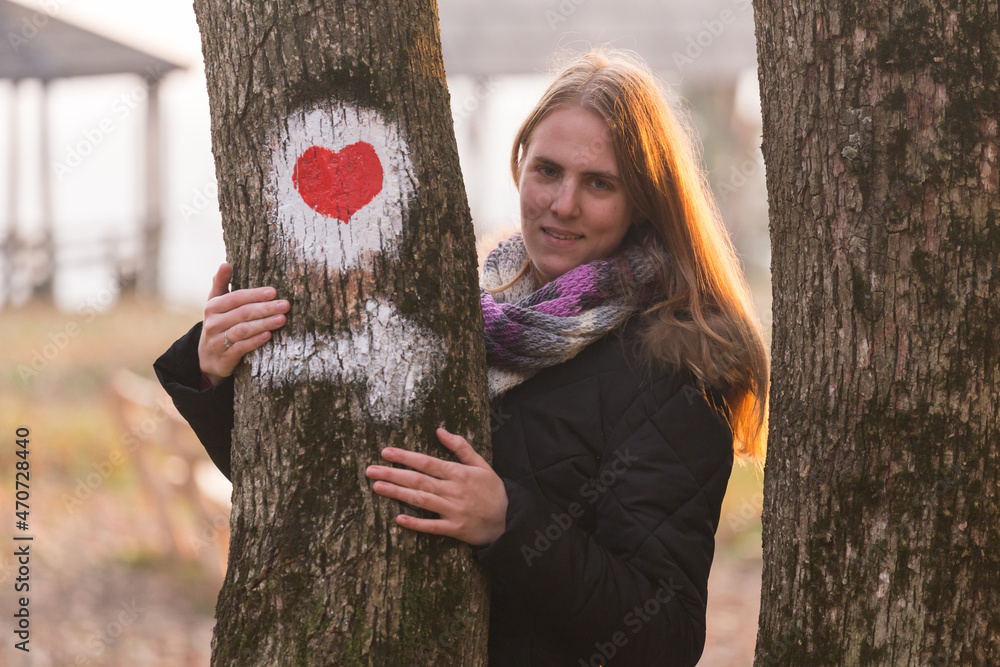 Young woman hug a tree in the forest whit a sign of heart and love for ...