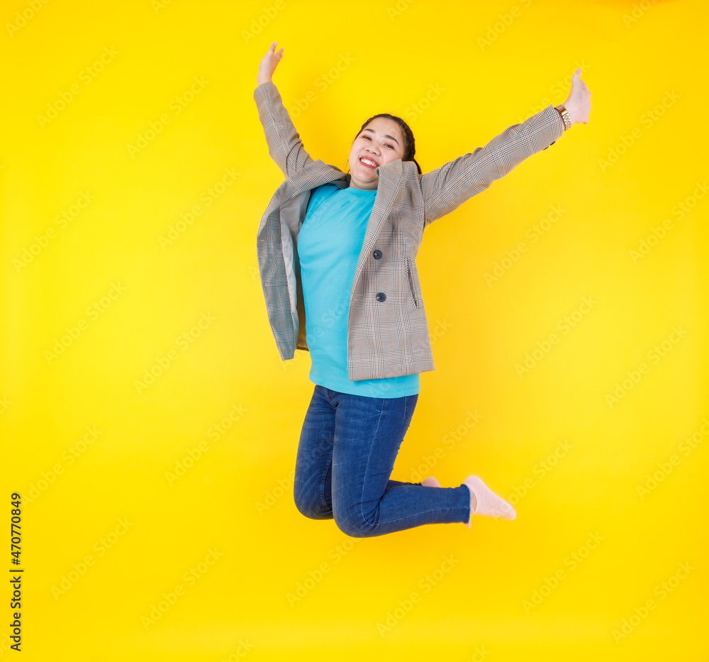 Lively young Asian girl cheerfully jumping up high to fly in air as ...
