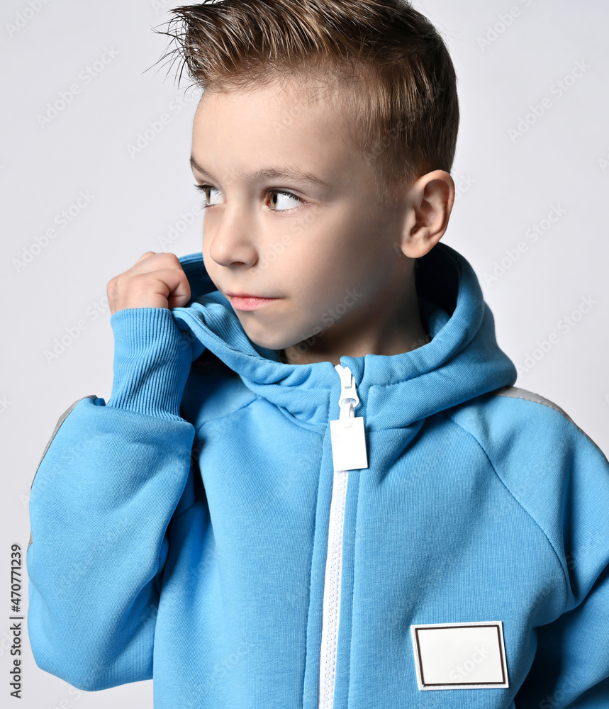 Closeup of kid boy in blue jumpsuit or hoodie with zipper standing with ...