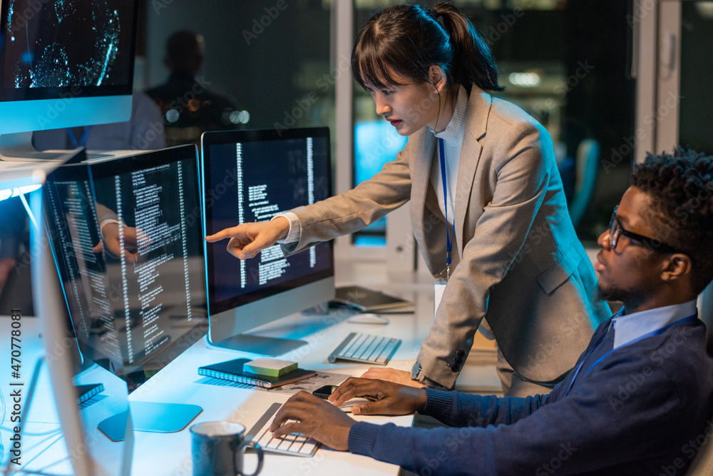 Young Asian female it-engineer pointing at data on computer screen ...