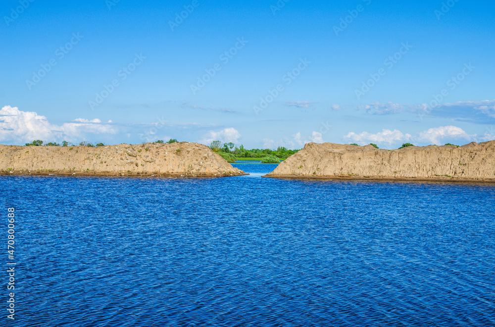 Mound of poor-quality sand on the border of the flooded career where ...