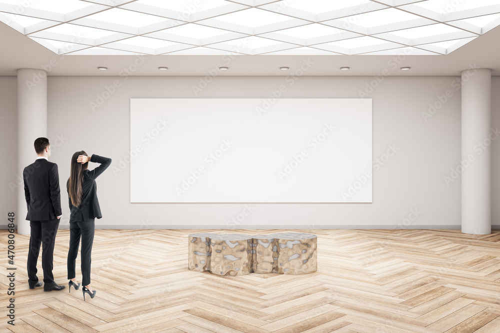 Businessman and woman looking at wall in modern exhibition hall ...