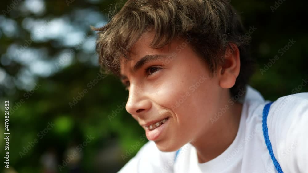 Smiling handsome young boy portrait face close-up outside in sunny day ...