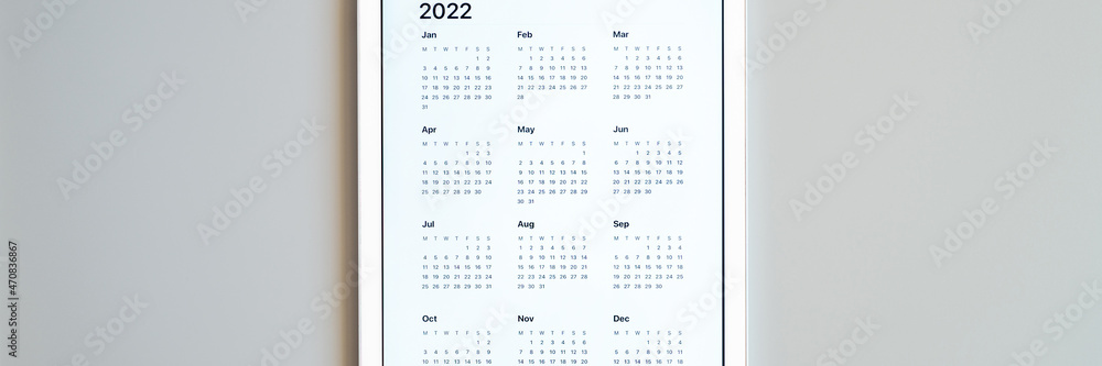 tablet computer with an open app of calendar for 2022 year on a gray ...