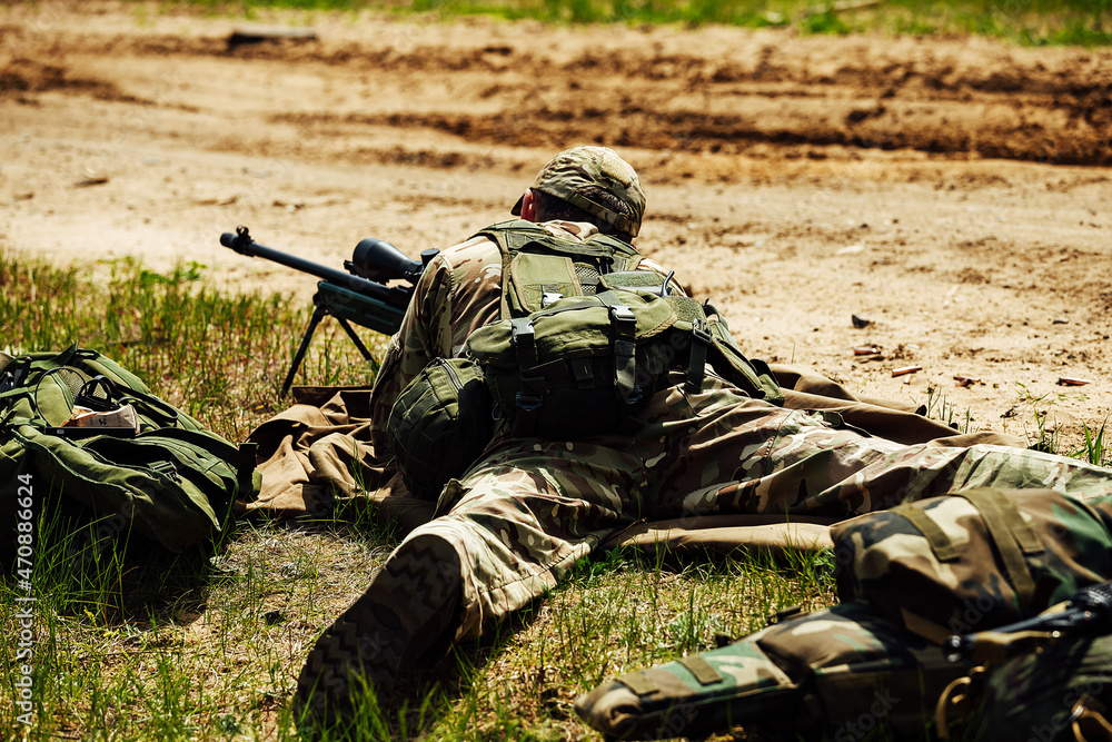 a sniper shoots lying down with a rifle with an optical sight. the ...