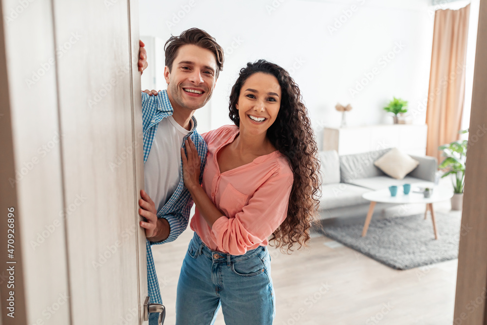 Foto de Cheerful couple inviting people to enter home do Stock | Adobe ...