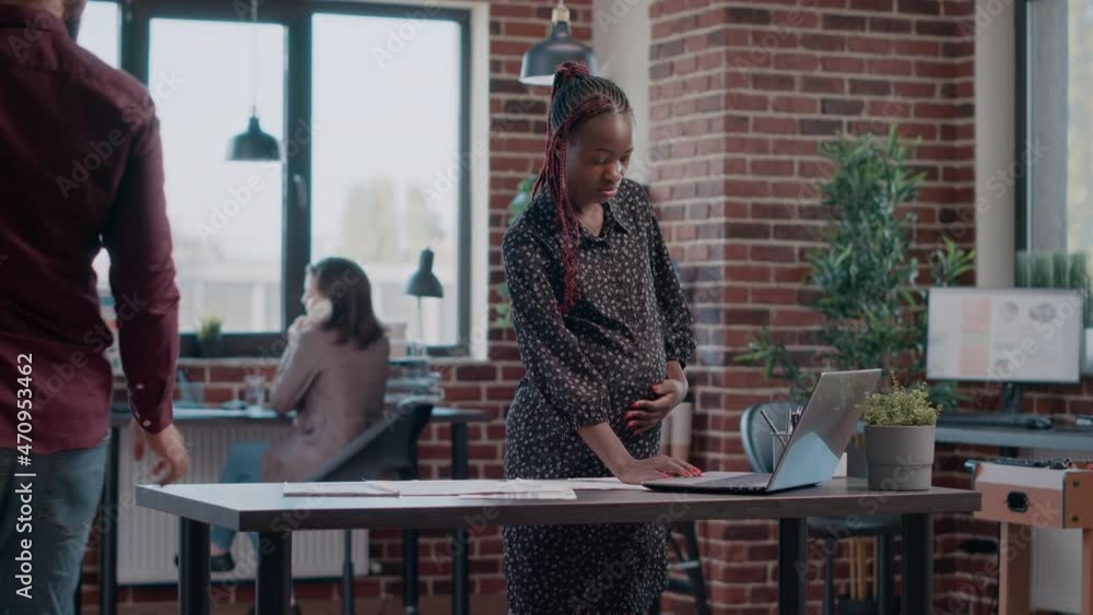 Business man helping pregnant woman with project planning at workplace ...