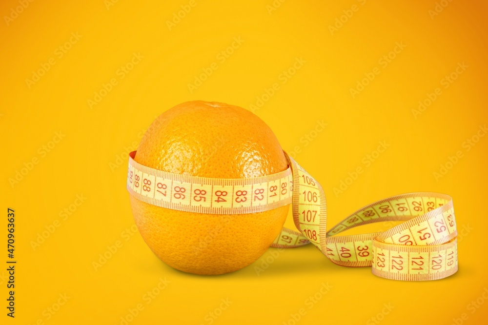 Fruit orange is wrapped with measuring tap as a symbol of cellulite on ...