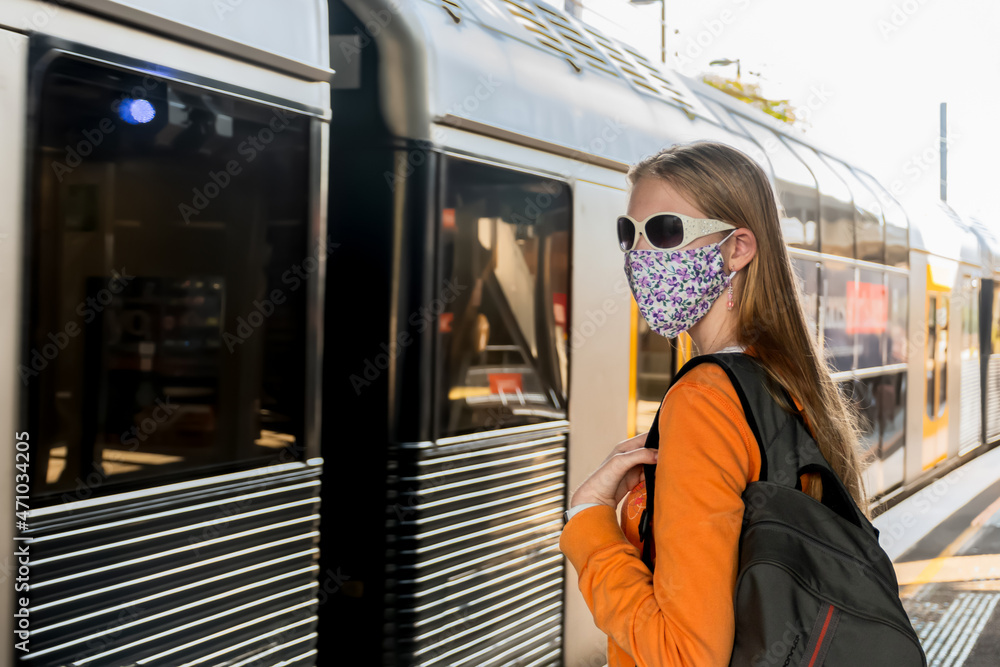 Teenage girl wearing face mask waiting for the train on the platform ...