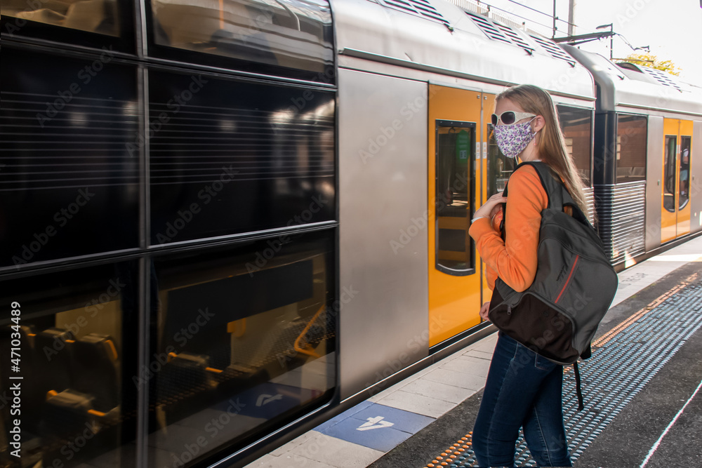 Foto de Teenage girl wearing face mask waiting for the train on the ...