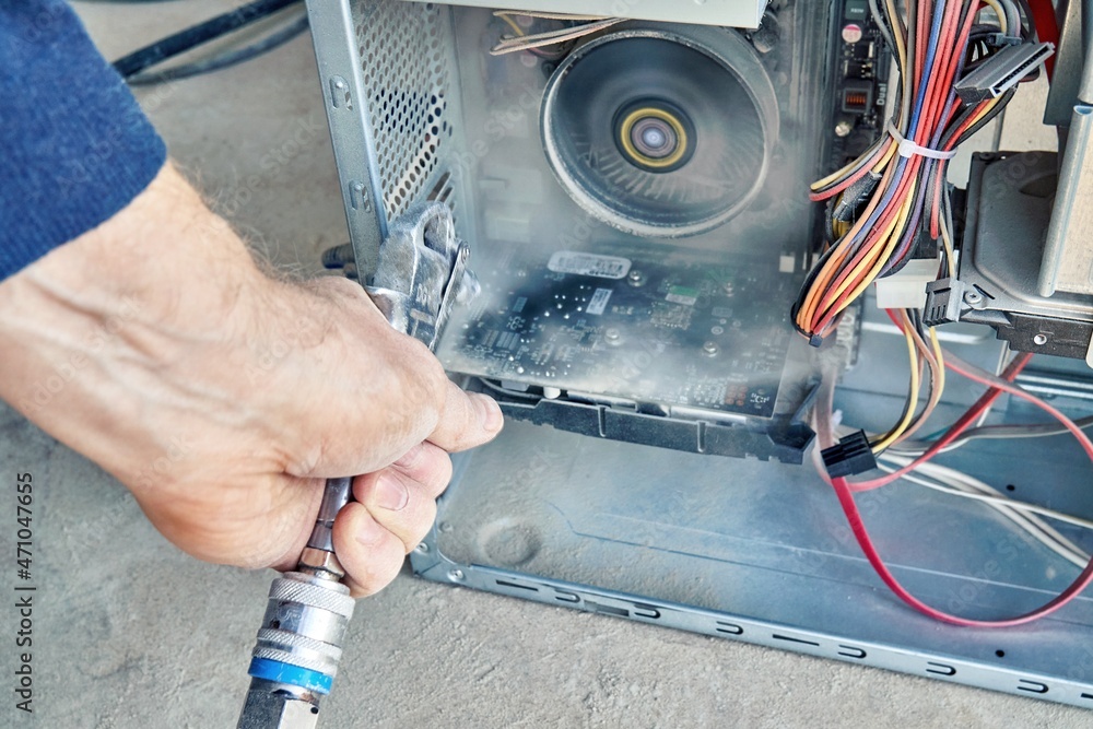 Employee cleans an open old computer with air duster cleaning spray gun ...