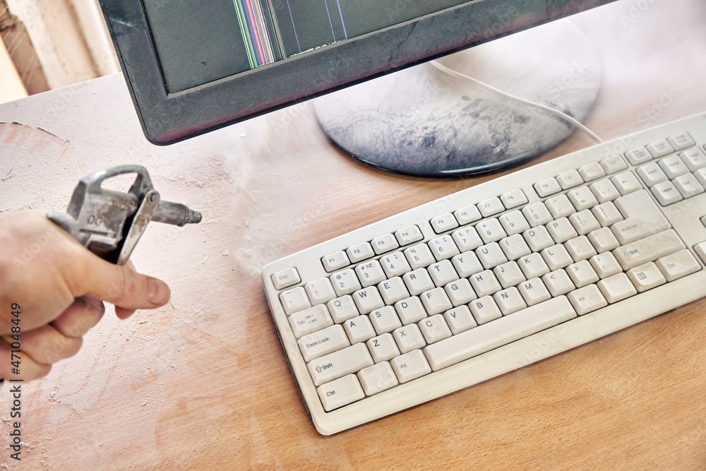 Employee cleans a dusty keyboard and dusty desk with air duster ...