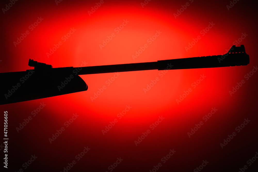 Silhouette of weapons on a red and black background. Part of a rifle ...