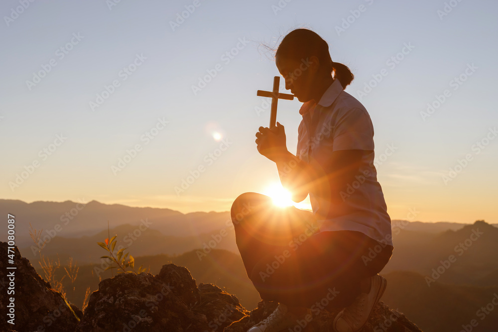 Silhouette young woman praying and holding Christian cross for ...