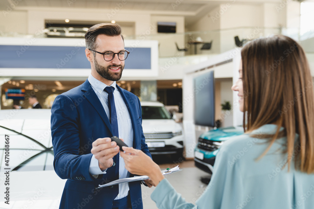 Handsome caucasian male shop assistant in formal clothes giving car ...