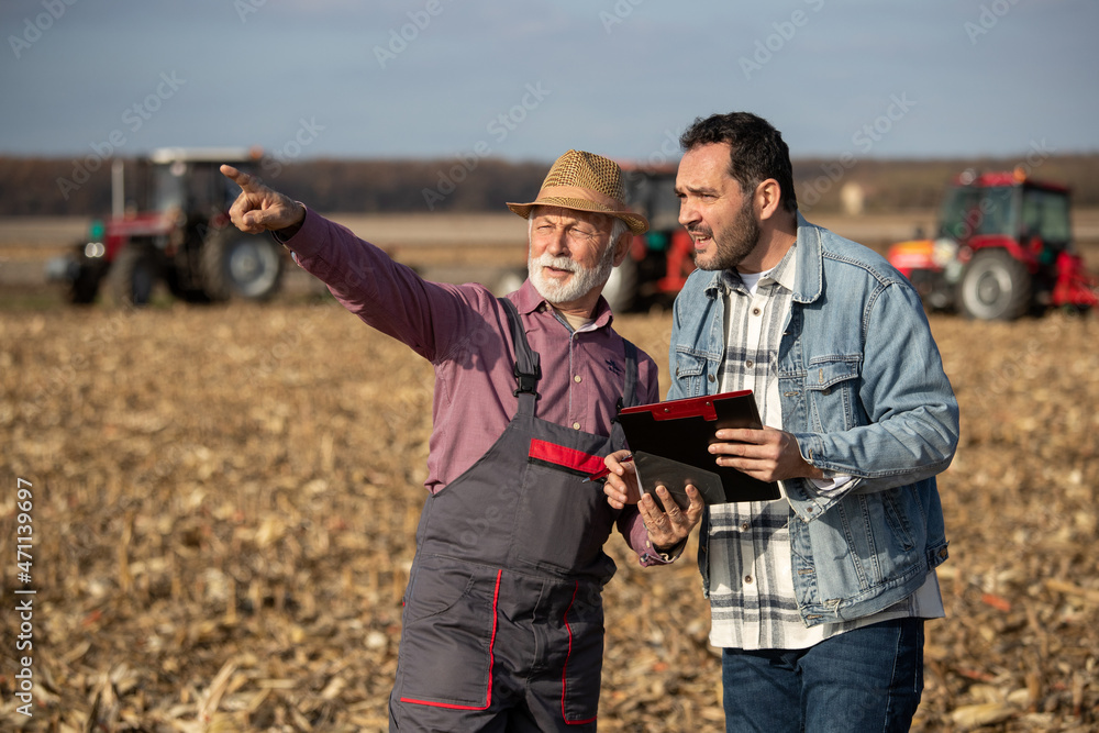 Farmers talking in field in front of tractors Stock Photo | Adobe Stock