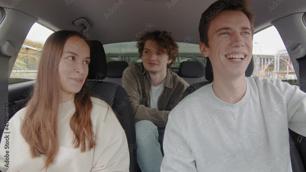A small group of people are riding in a car, smiling and looking around ...