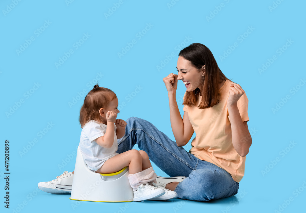 Mother potty training her little daughter on color background Stock ...