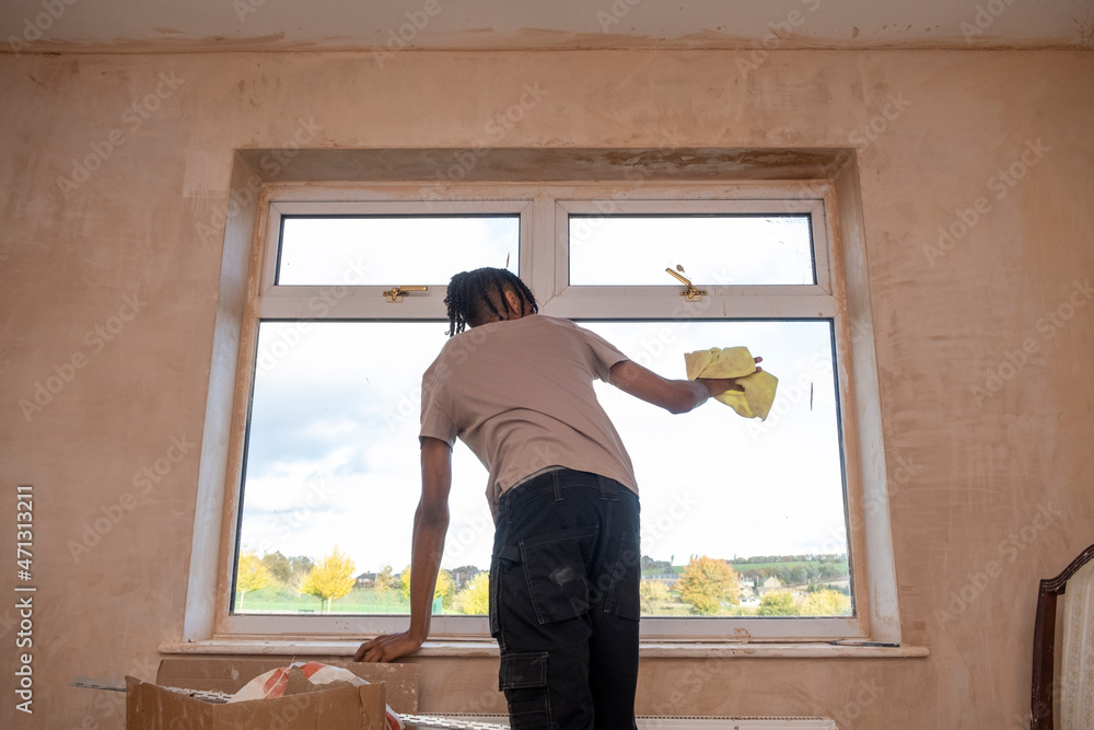 Rear view of teenage boy washing window in house under renovation Stock ...