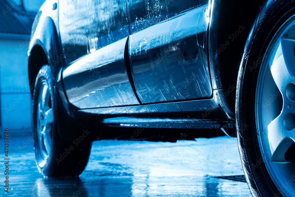 Car wash under high pressure. Close up side view of gray car after ...
