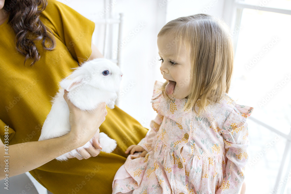 Foto de A little daughter with her mother and a white rabbit. A little ...