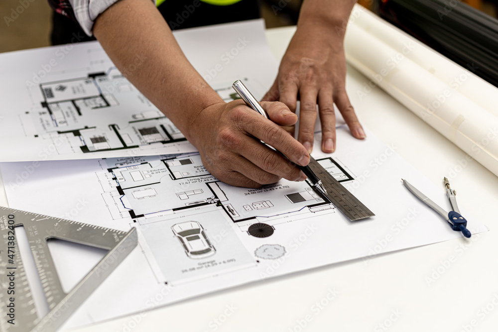 Architect uses a ruler to measure the blueprints of the houses he ...