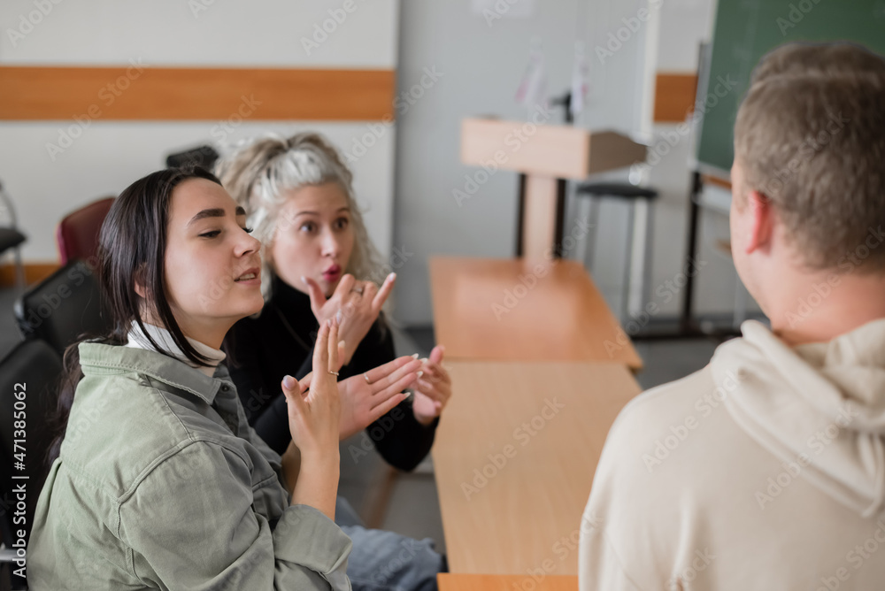 Two girls and a guy are talking in sign language. Three deaf students ...