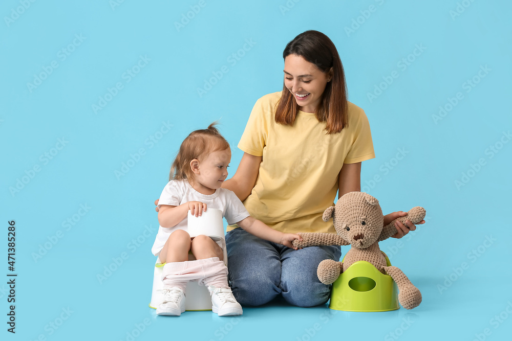 Mother potty training her little daughter on color background Stock ...