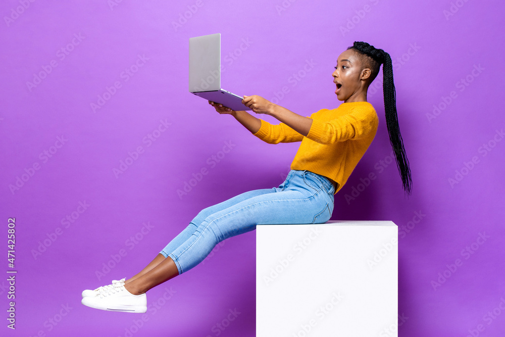 Excited African American woman holding and watching laptop computer ...