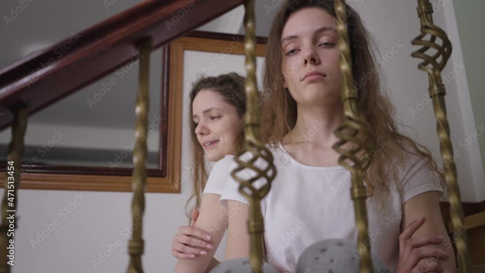 Portrait of upset Caucasian young woman sitting on stairs with twin ...