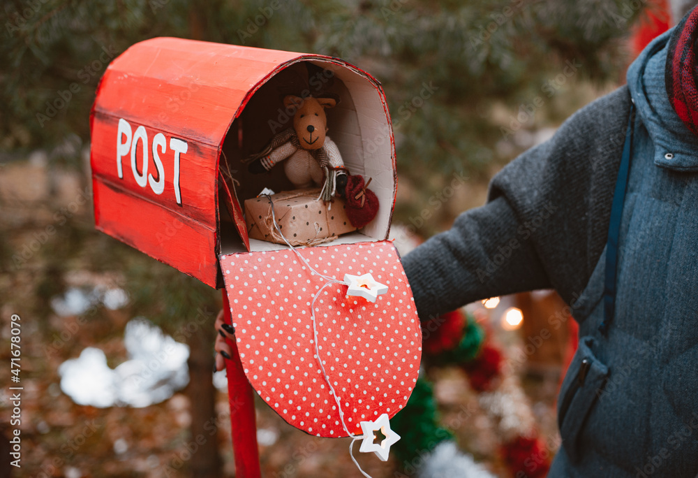woman holds a red polka dot retro mailbox with Christmas gifts toys as ...