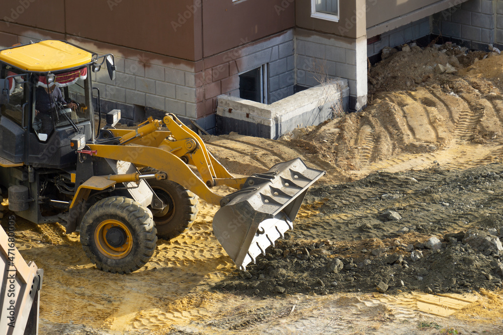 Bulldozer bucket dumps rubble on a construction site. A tractor with a ...