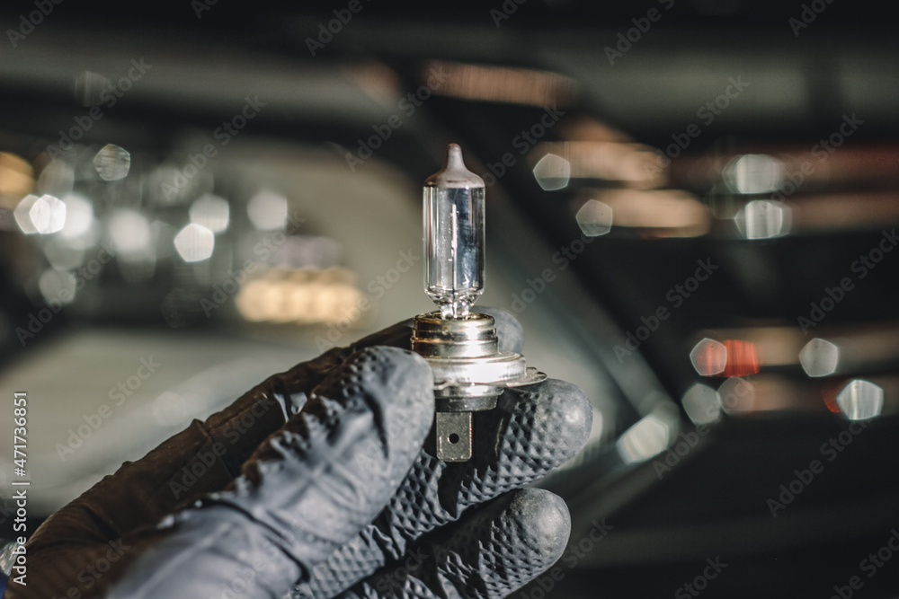 Halogen light bulb H4 above the black car. A professional worker ...