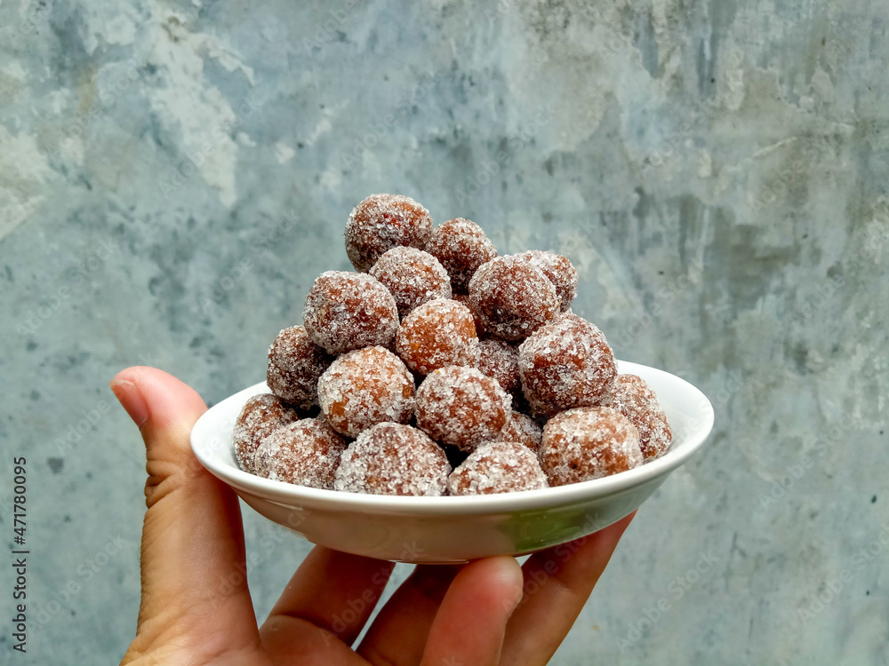 Tamarind candy, placed inside white small plate. Sweet and sour candy ...