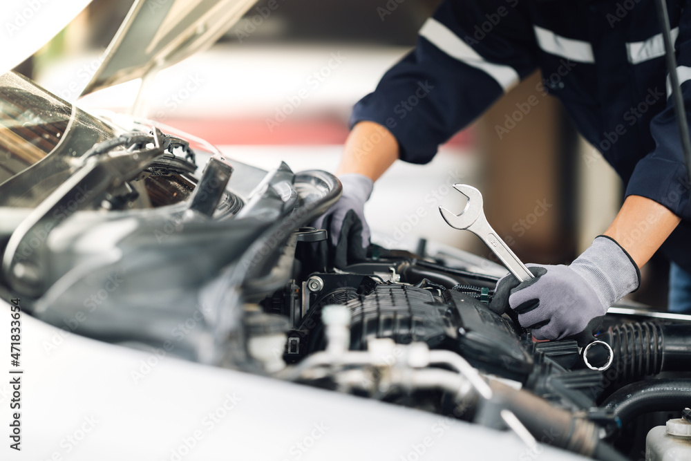 Foto de Mechanic works on the engine of the car in the garage. Repair ...