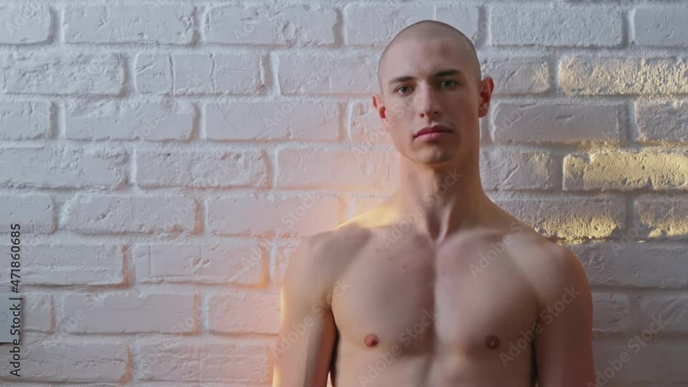 Young bald shirtless handsome homosexual man posing over the white wall ...