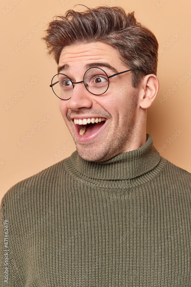 Happy surprised young man looks gladfully away reacts on awesome scene ...