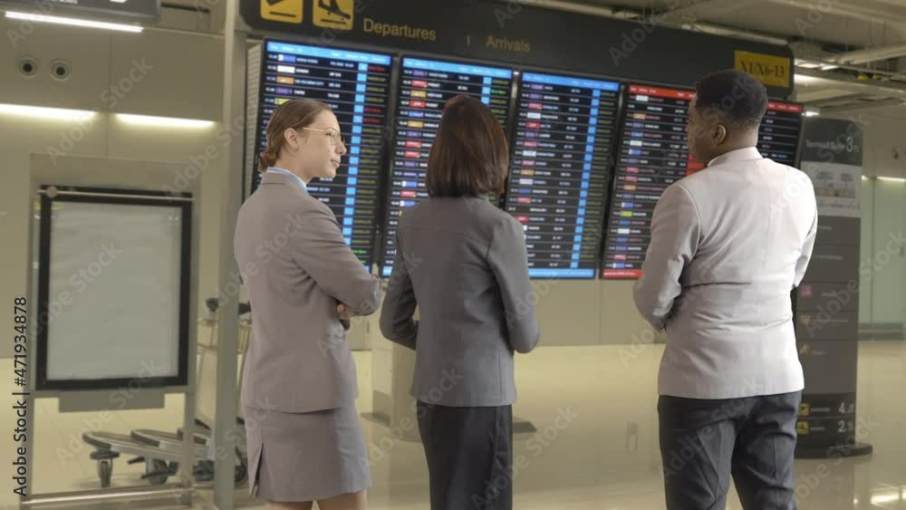 Airline flight crew standing in front of display schedule flight board ...