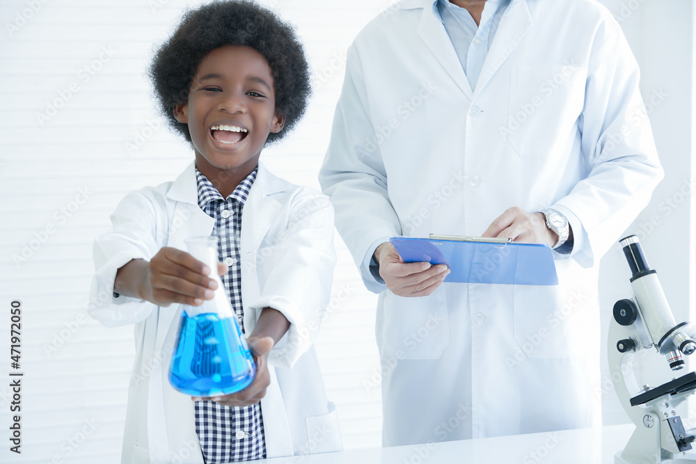 Little African kid boy scientist showing test bottle with chemistry ...