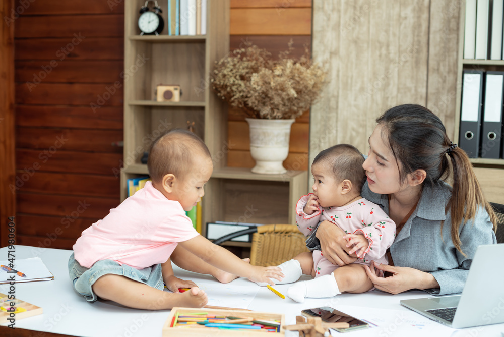 Foto de Busy woman trying to work while babysitting two kids. Young ...
