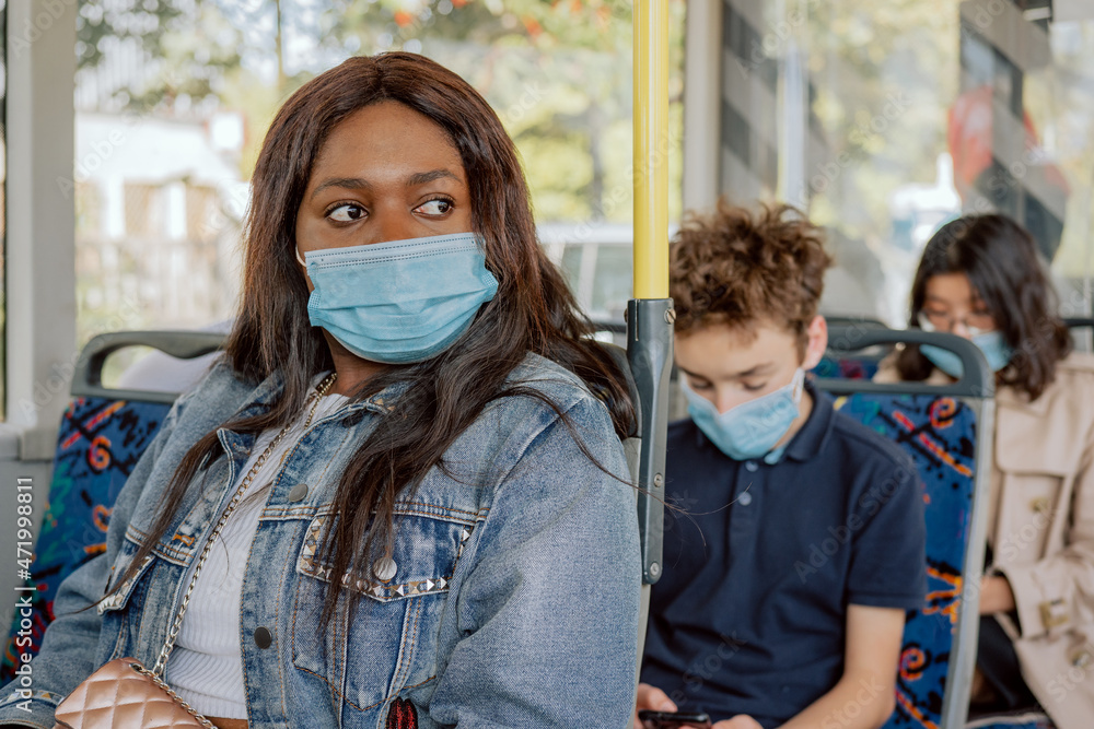 Young dark-skinned woman dressed in denim jacket sits on bus public ...