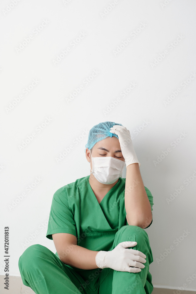 Stressed exhausted surgeon sitting on the floor with eyes closed after ...
