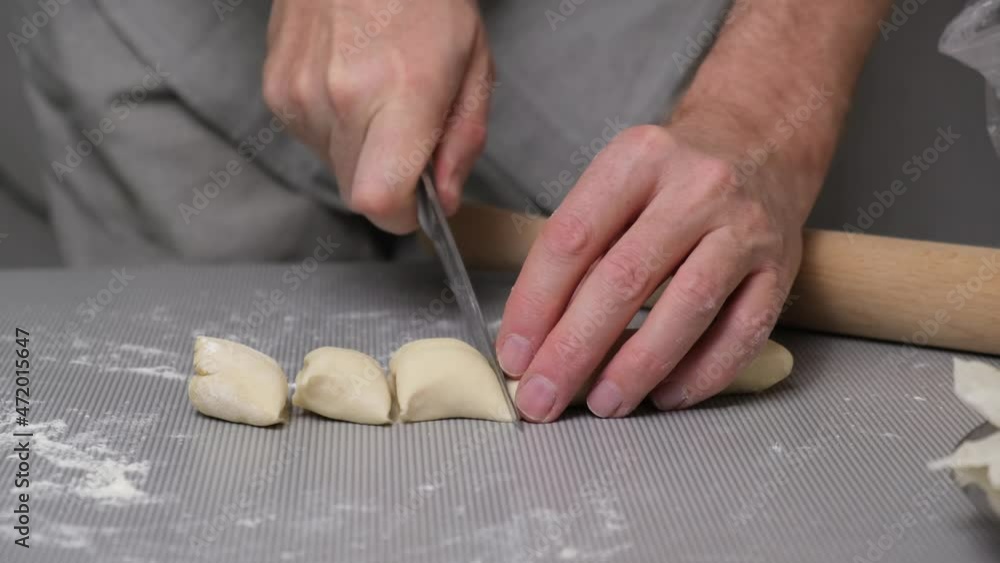 4K Close-up of the chef's hands cut a strip of dough into pieces and ...