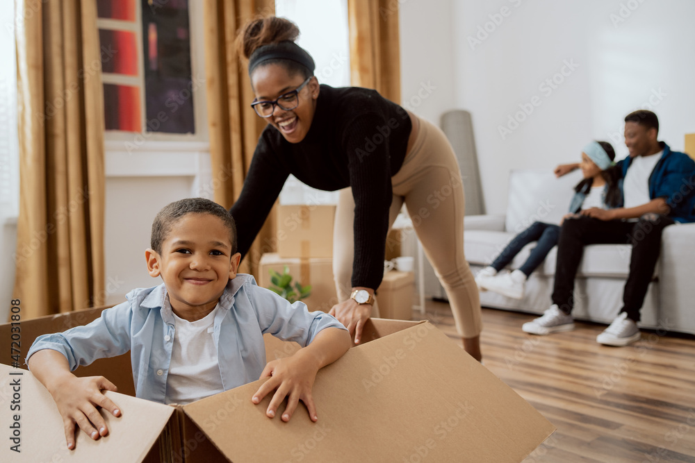 Mom playing with baby, pushing a cardboard box across the living room ...