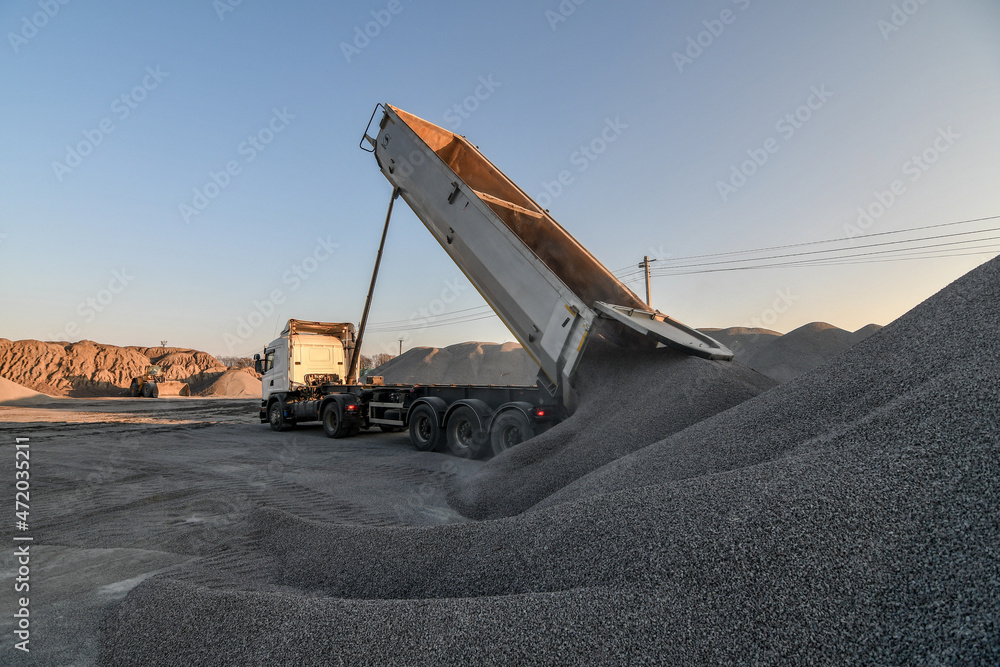 Heavy dump truck unloading gravel on industrial quarry production site ...