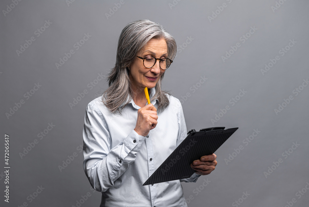 Modern elderly senior woman in formal wear taking notes standing with ...