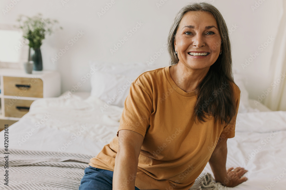 Sweet, adorable modern grandmother in casual T-shirt and jeans laughing ...
