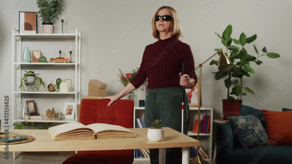 Blind woman reading braille book using fingers, sitting in living room ...